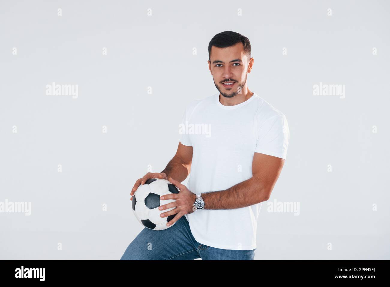 Football fan with soccer ball. Young handsome man standing indoors ...