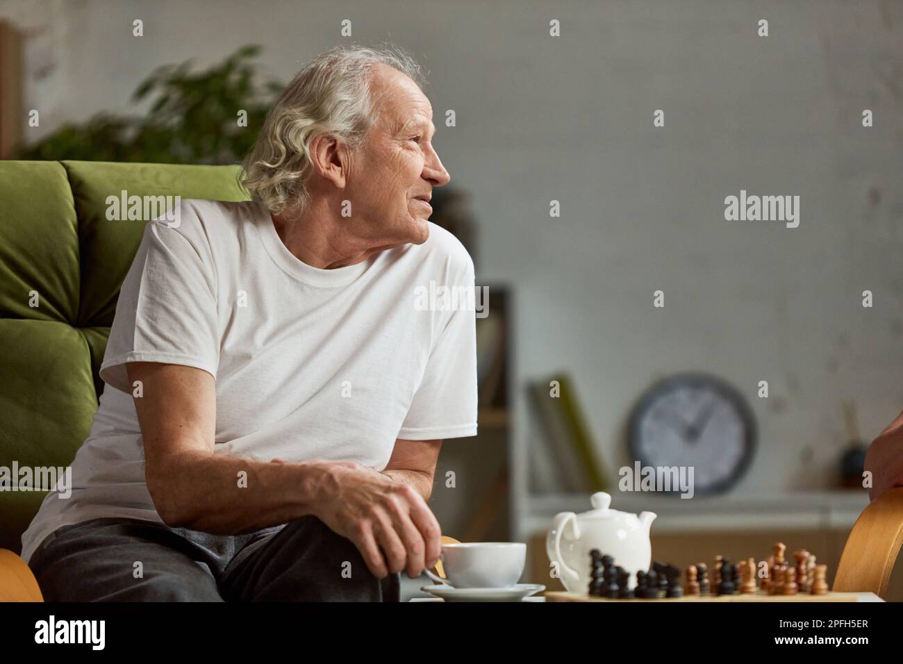 Senior, old, retired man sitting on chair at home, playing chess ...