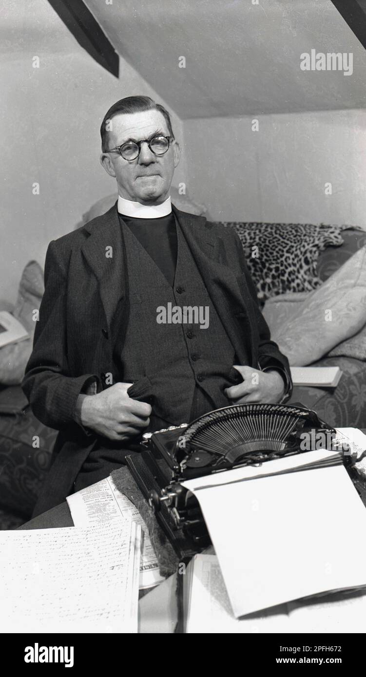 1940s, historial, a priest or vicar, wearing a clerical collar, stting ...