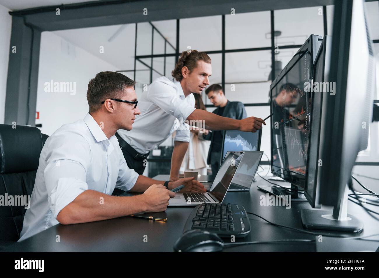 Guy in glasses concentrated at work. Team of stockbrokers is in modern ...
