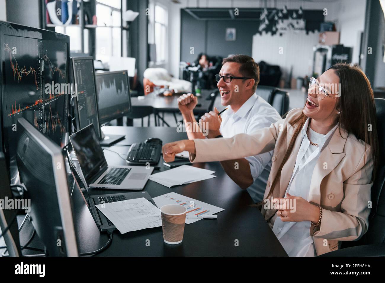 Celebrates success. Team of stockbrokers works in modern office with ...