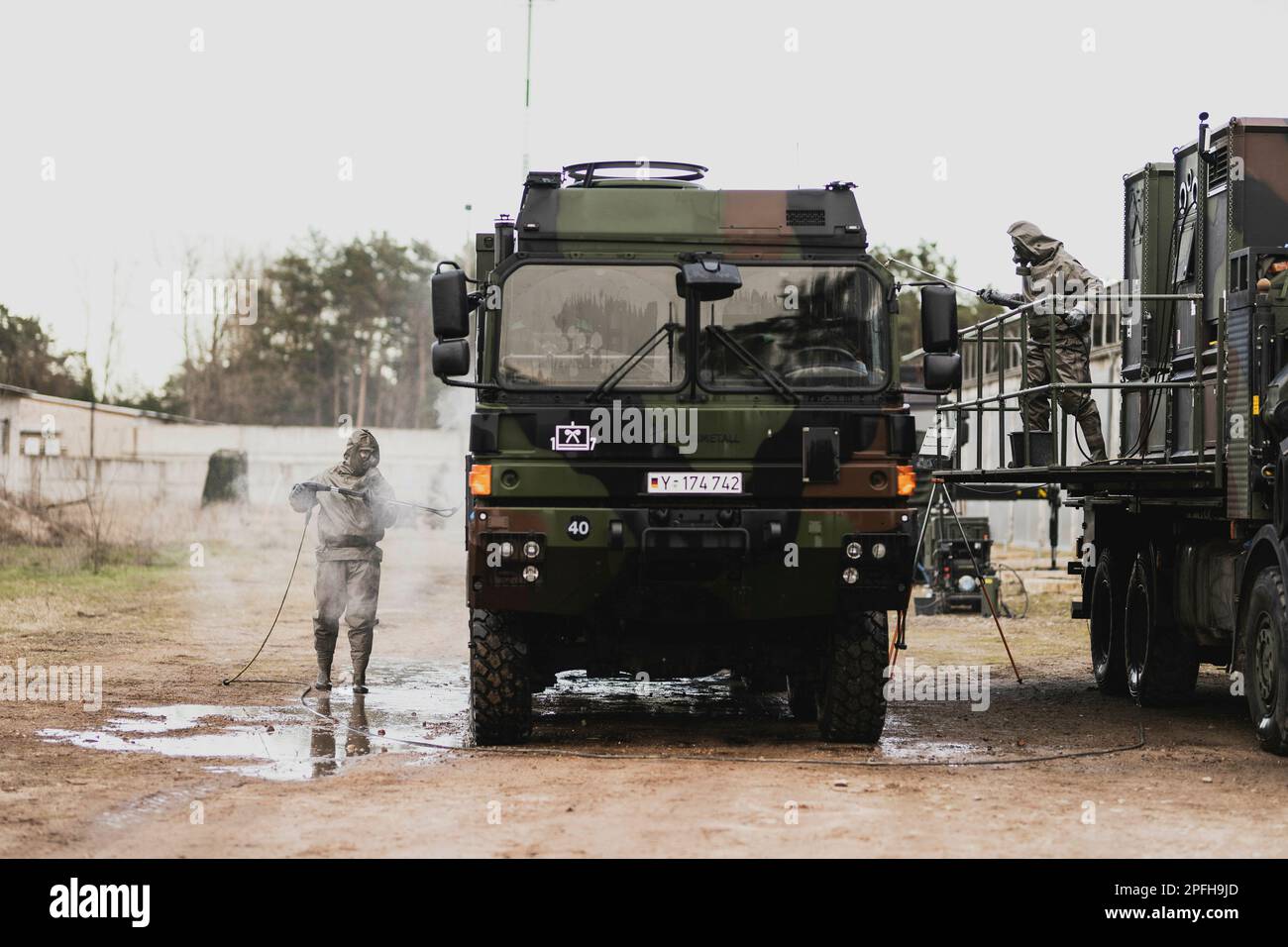Two NBC defense soldiers in protective gear, pictured decontaminating a ...