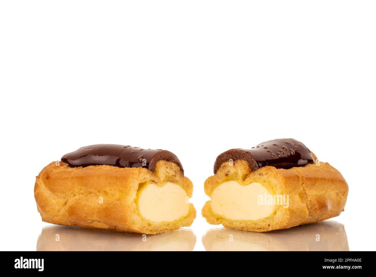 One sweet chocolate eclair cut in half, close-up, isolated on white ...