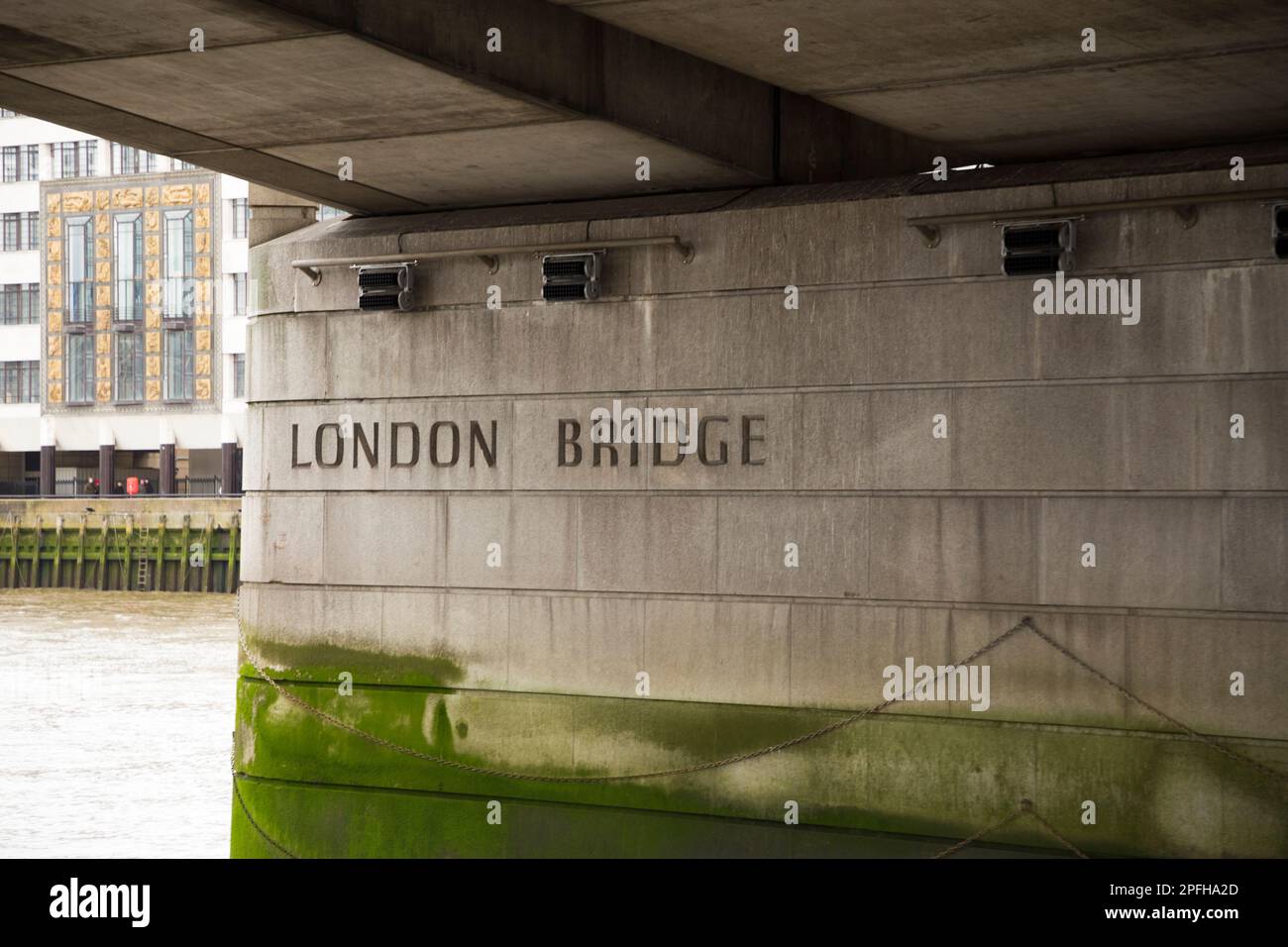 Name sign on London Bridge written into the pier and seen from boat ...