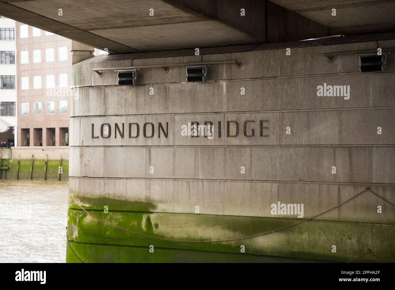 Name sign on London Bridge written into the pier and seen from boat ...