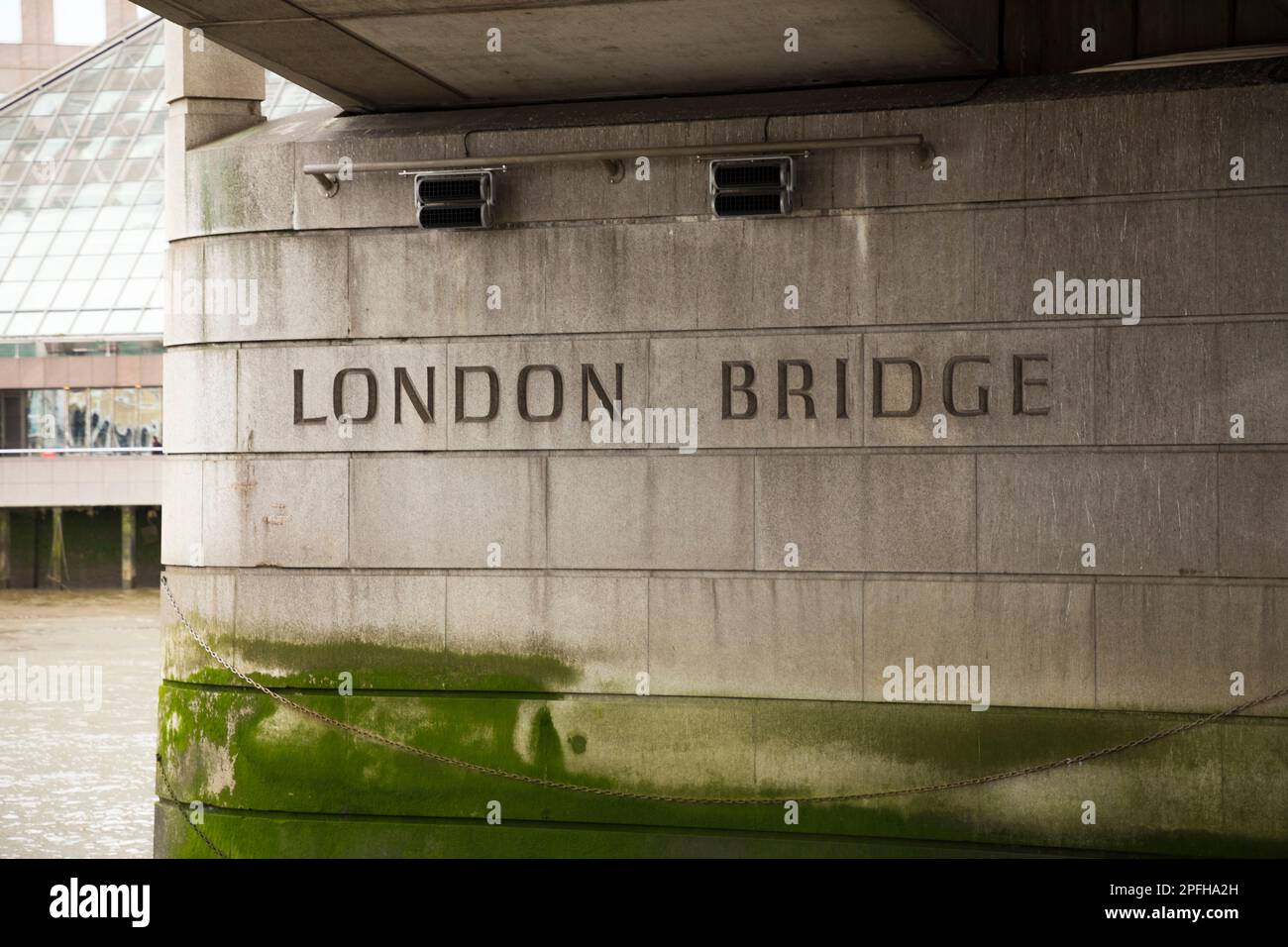 Name sign on London Bridge written into the pier and seen from boat ...