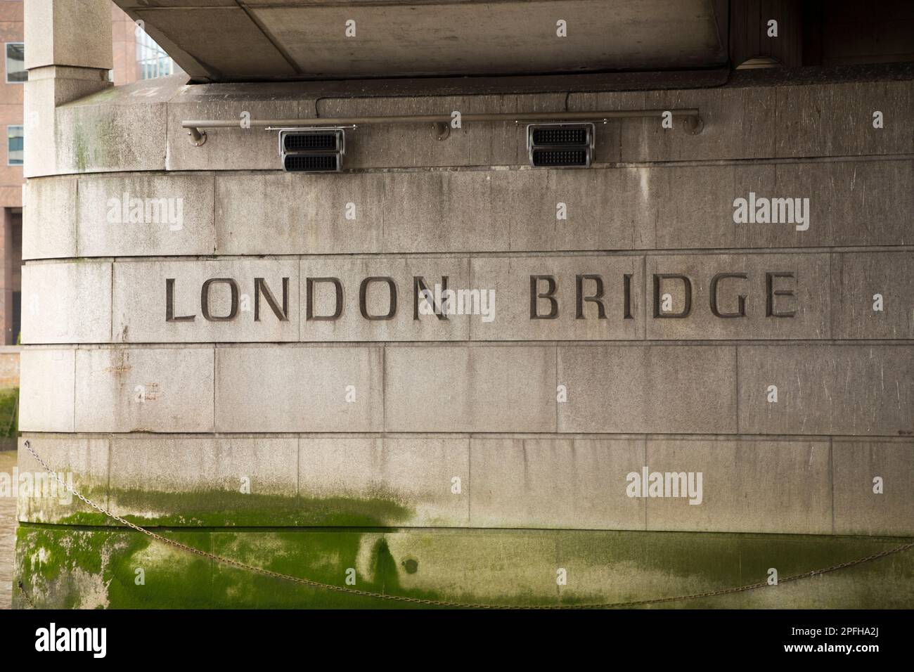 Name sign on London Bridge written into the pier and seen from boat ...