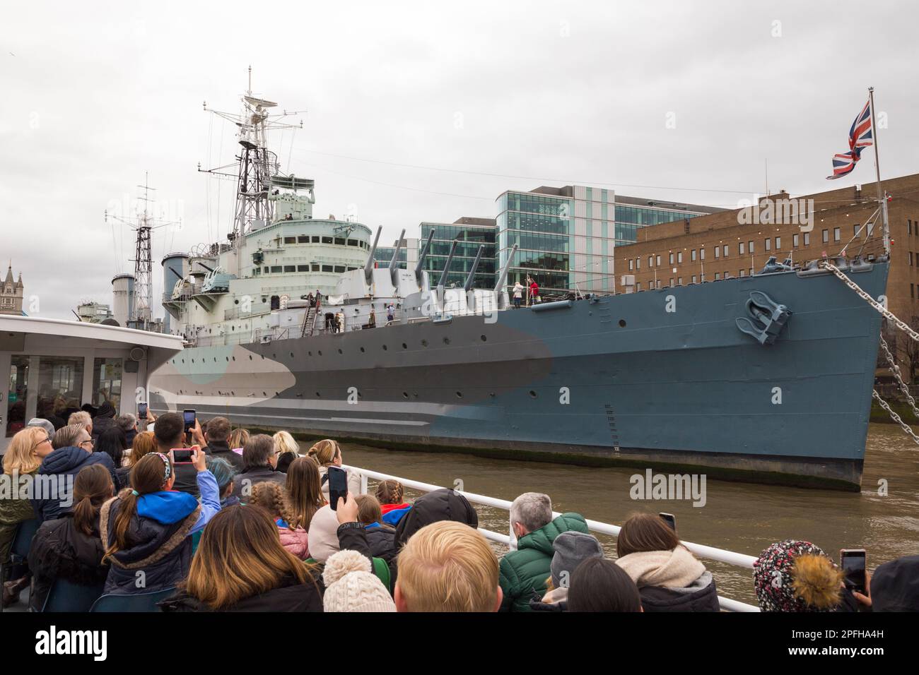 Tourist boat complete with tourists viewing HMS Belfast which is a Town ...