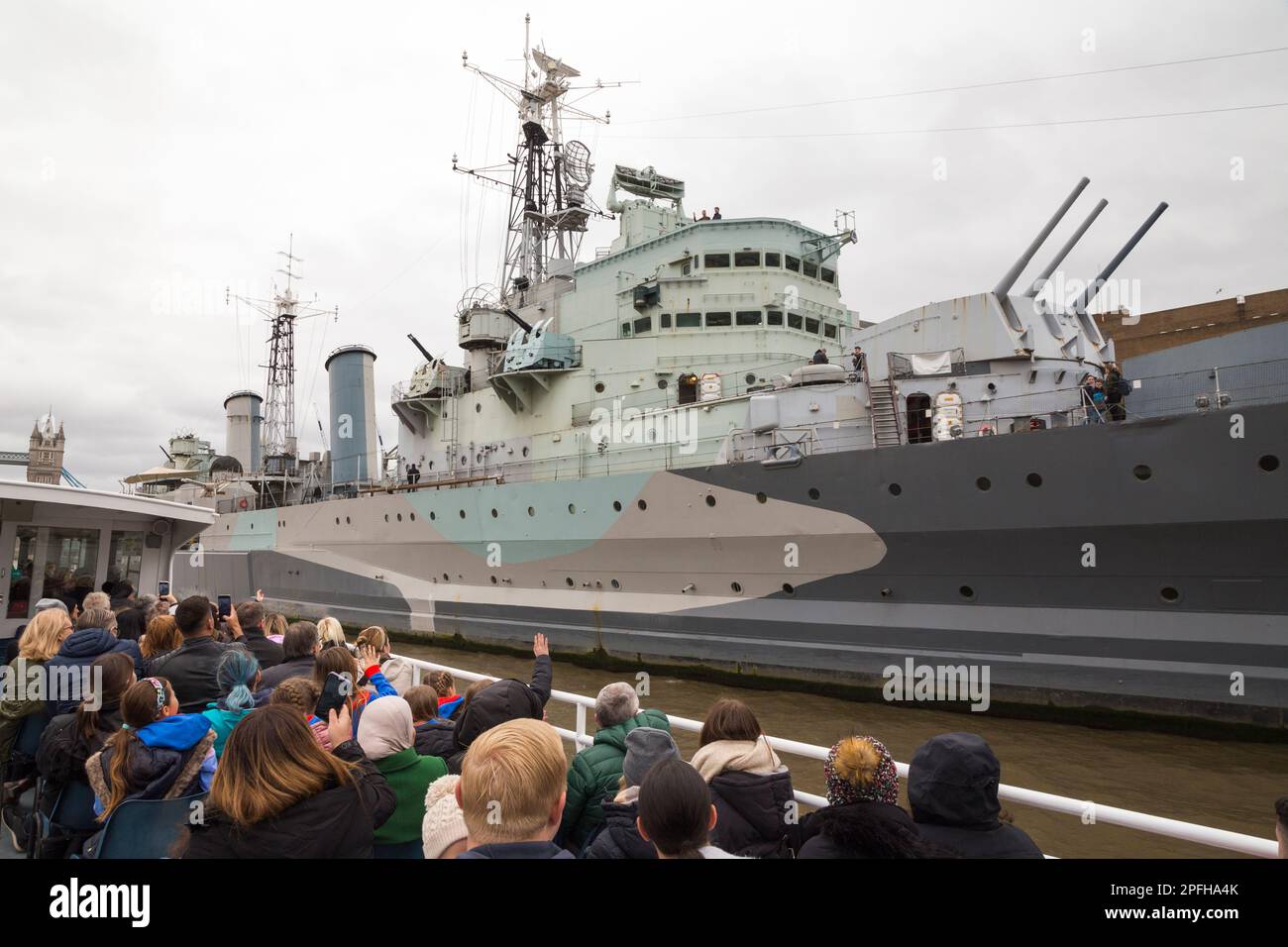 Tourist boat complete with tourists viewing HMS Belfast which is a Town ...