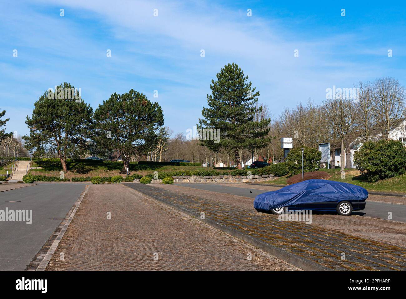 A lonely car is covered with a blue awning in an empty parking lot ...