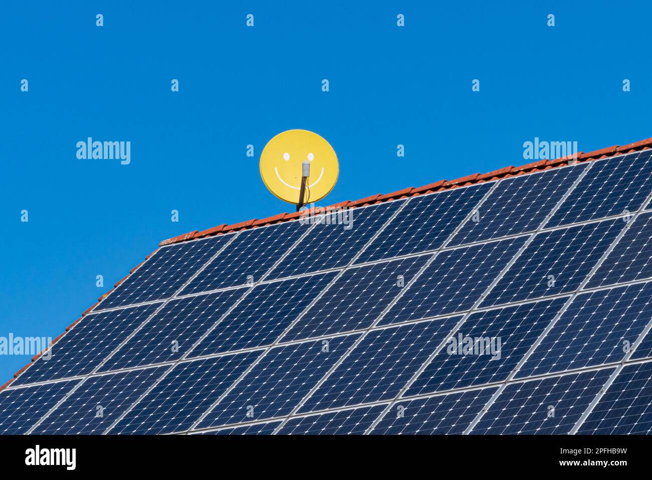 Satellite dish with a painted smile on the roof of a house. Solar ...