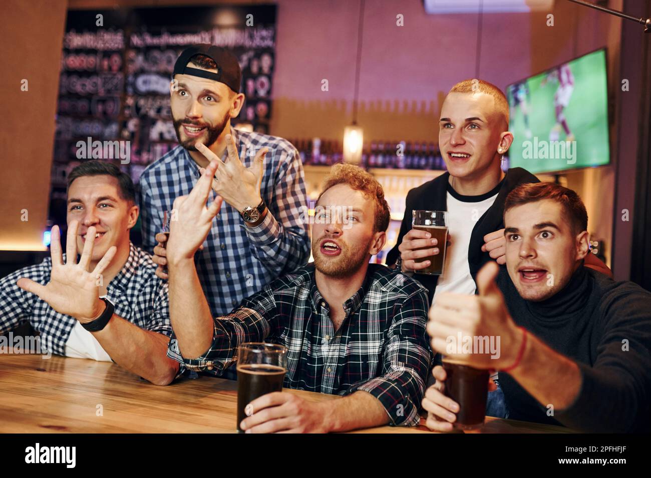Football fans watching TV. Group of people together indoors in the pub ...