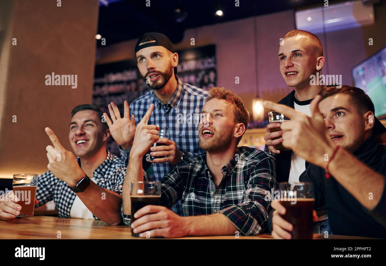 Football fans watching TV. Group of people together indoors in the pub ...