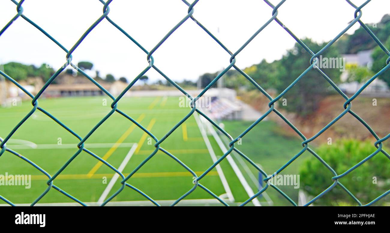 View of the Tiana soccer field through the wire fence, Tiana, Barcelona ...
