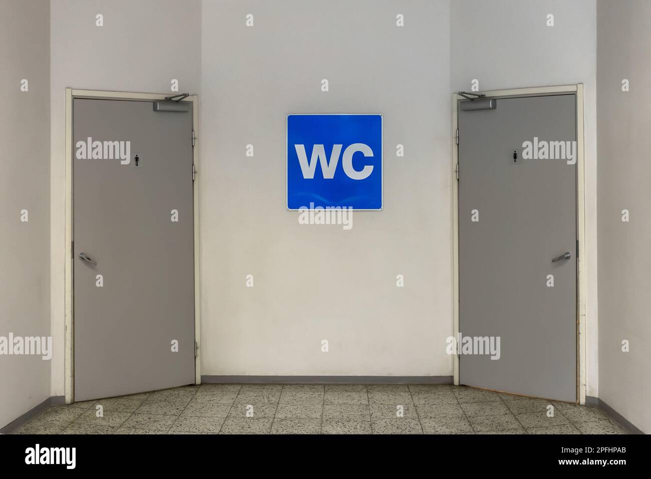 Blue WC sign on the white wall with two toilet doors on each side Stock ...