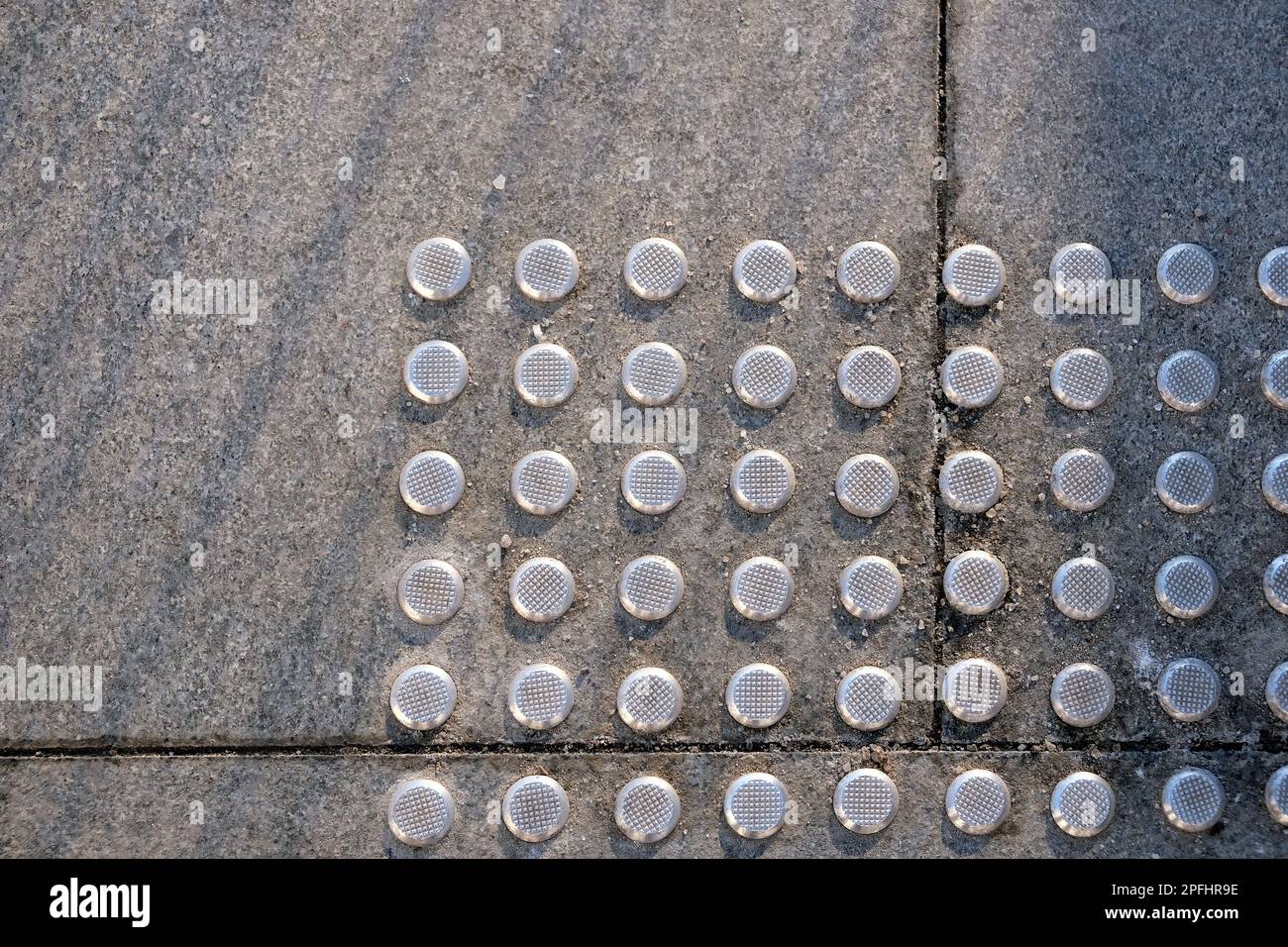 Many round metal marking on a granite plate pavement for people with ...