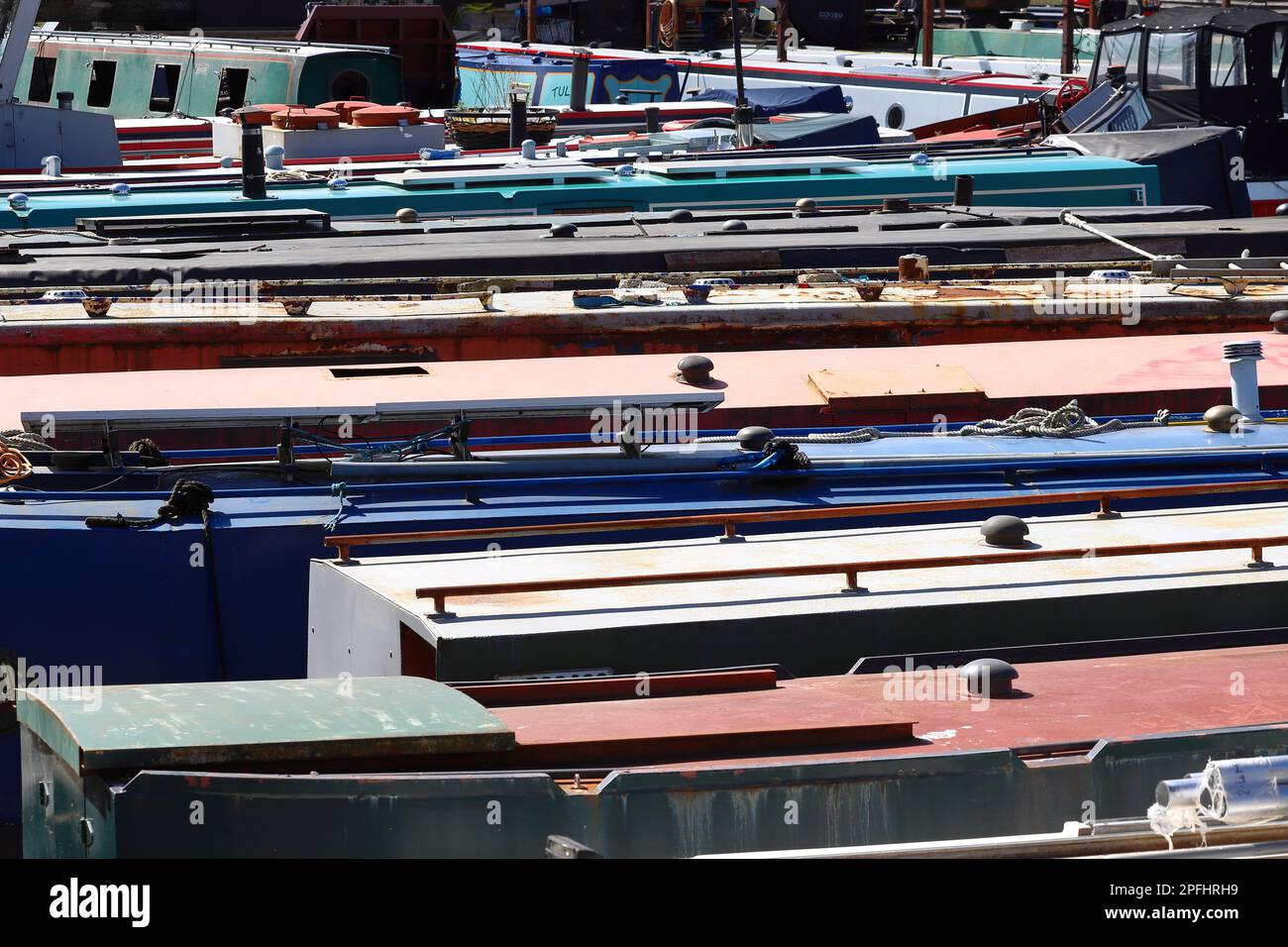 A collection of colourful narrowboats moored side by side in a boat ...
