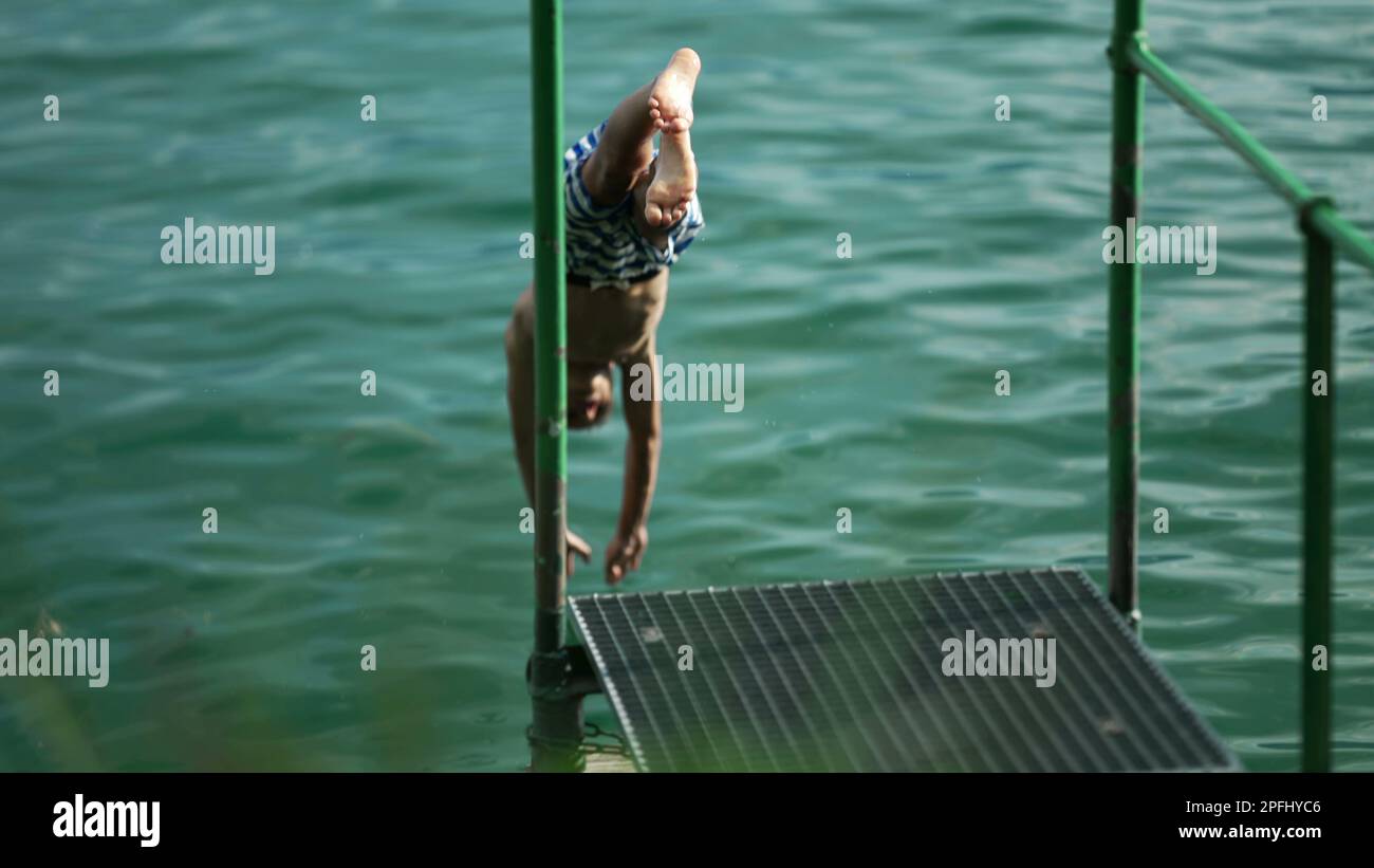 Young boy running diving into water. Teen child plunges in lake by dock ...