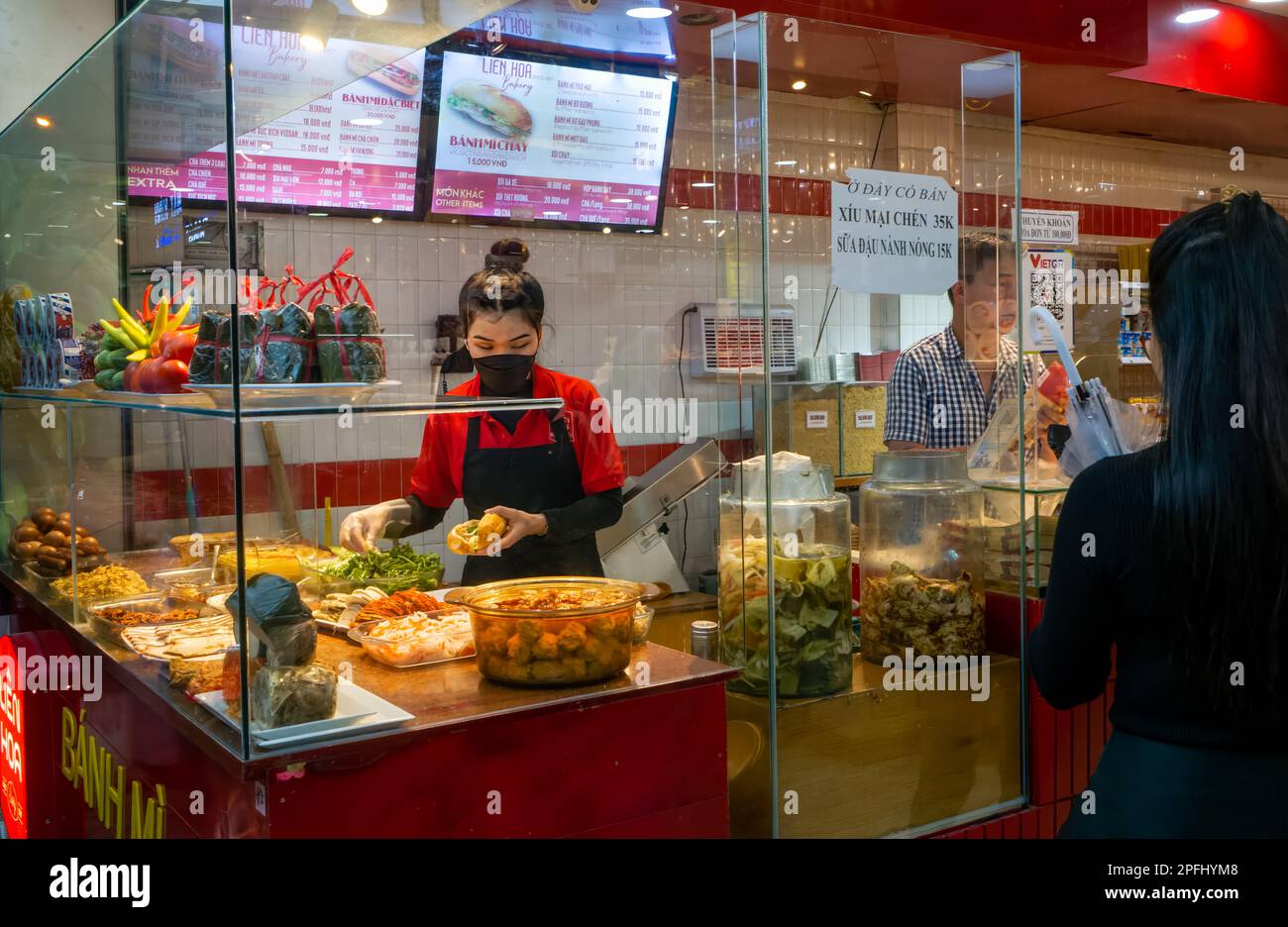 A young woman assistant in a bakery prepares a traditional Vietnamese ...