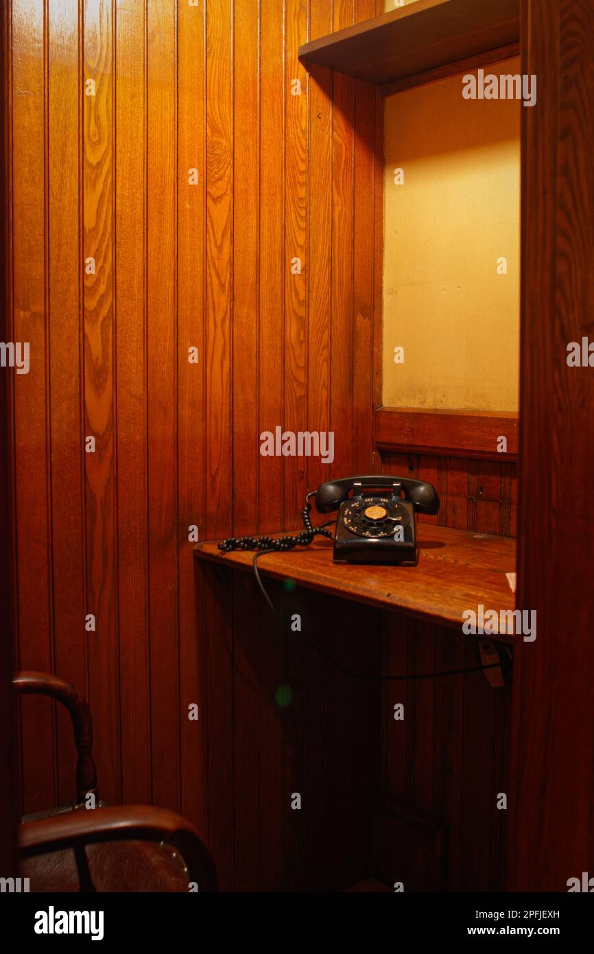 A dimly lit closet with wood paneling used as a vintage telephone room ...
