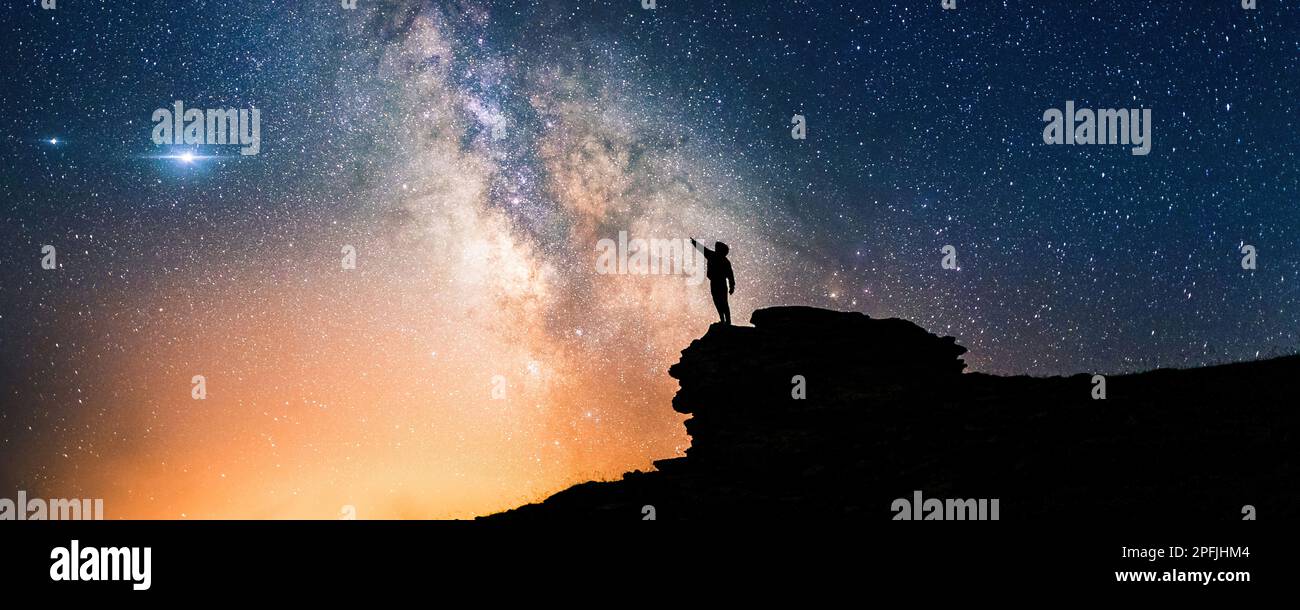 Lone person standing on top of rock, pointing with hand towards the ...