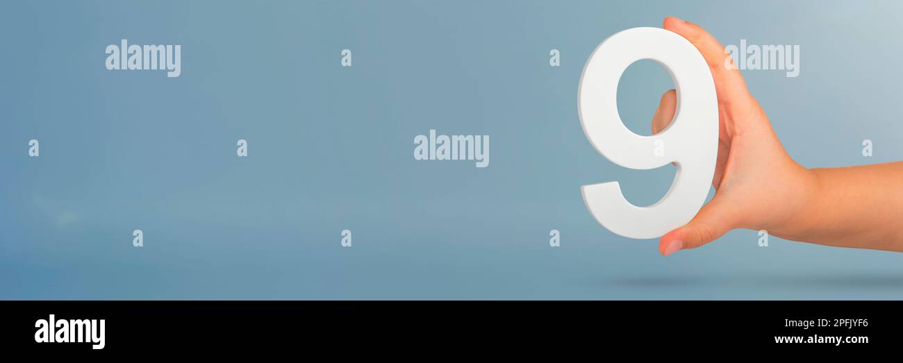 Number nine in hand. A hand holds a white number 9 on a blue background ...