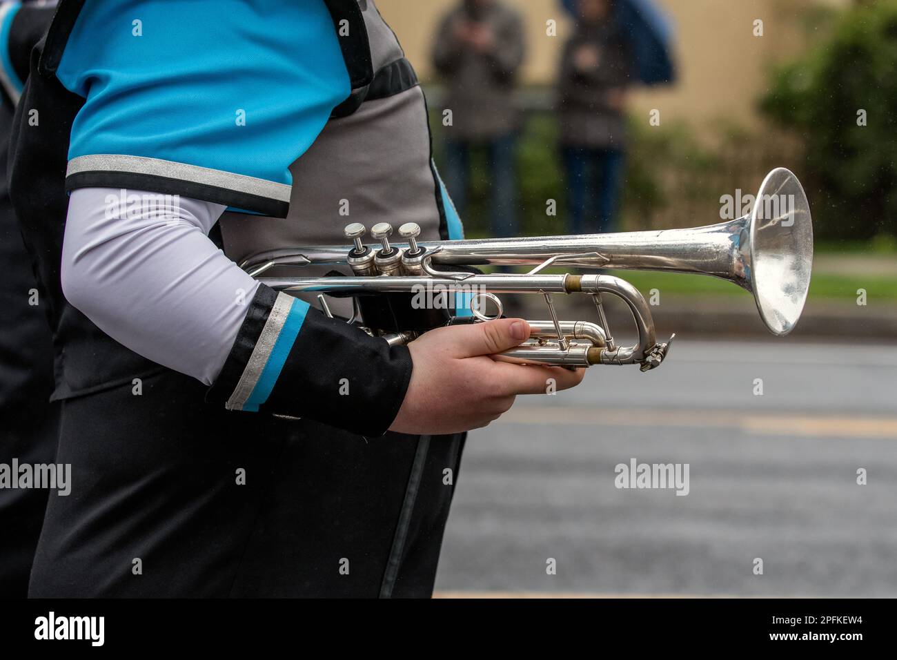 Trumphet player of marching band holding brass instrument at side while ...