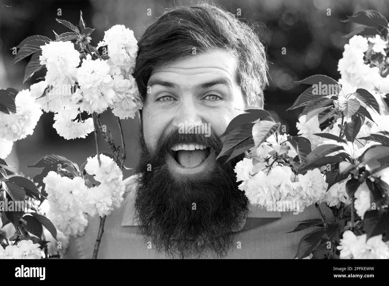 Outdoor partrait of young man surrounded by flowers. Spring blossom ...