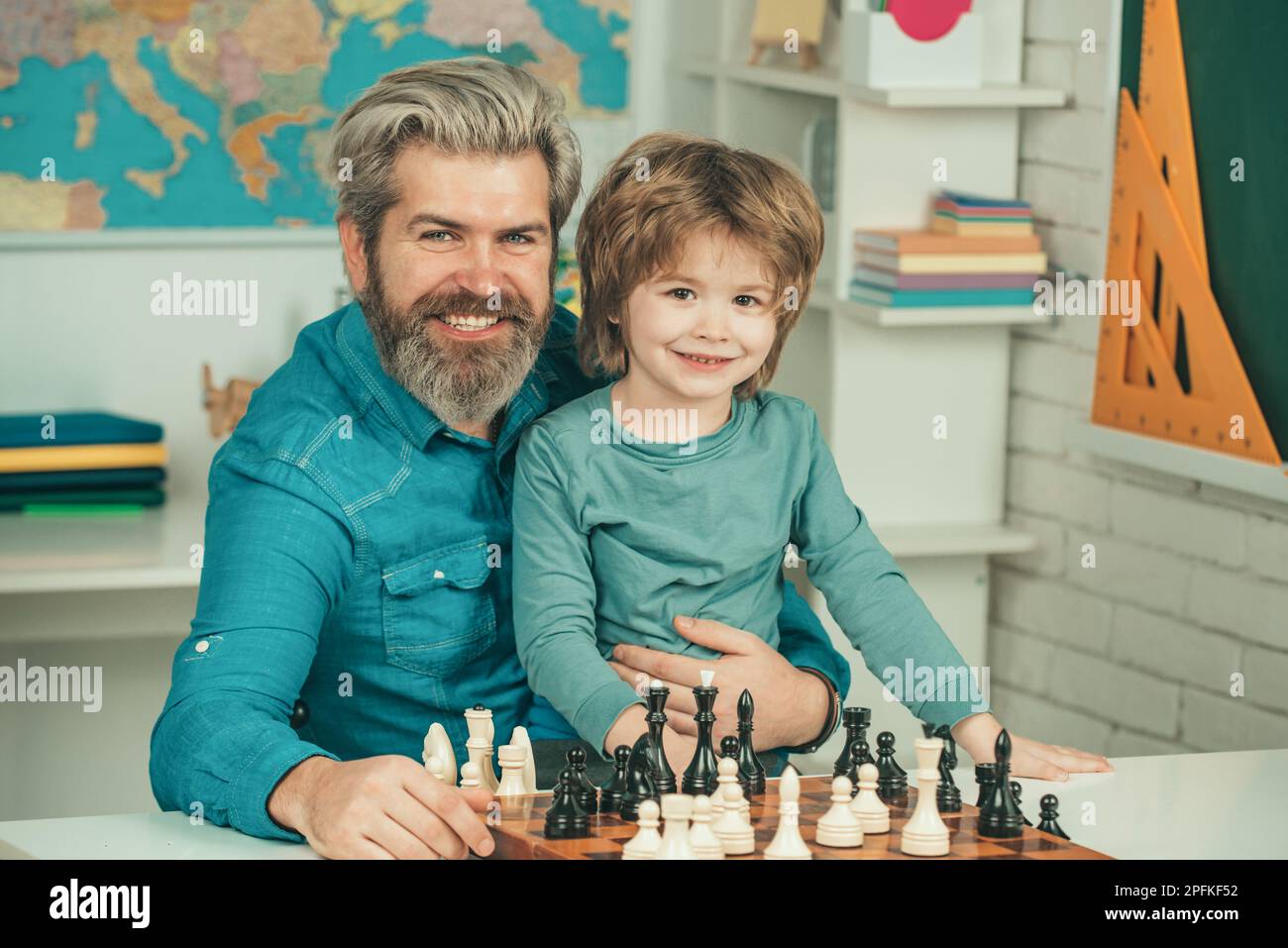 Teacher and schoolboy playing chess in class. Happy two generations of ...