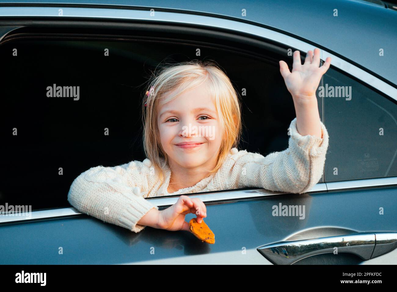 A little girl is sticking her head out the car window. Road trip or ...