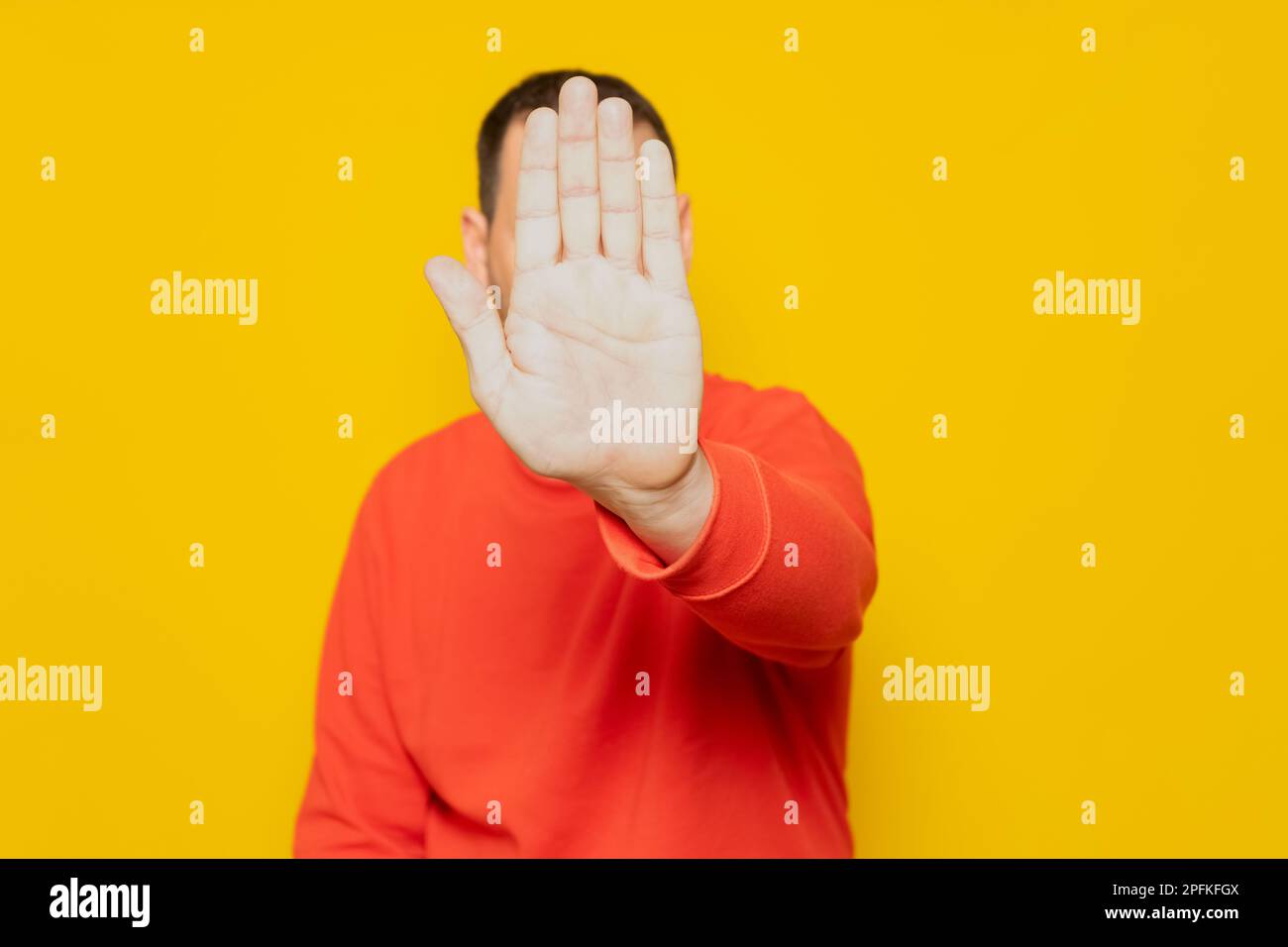 Hispanic man putting hand in front to stop camera, rejecting photos or ...