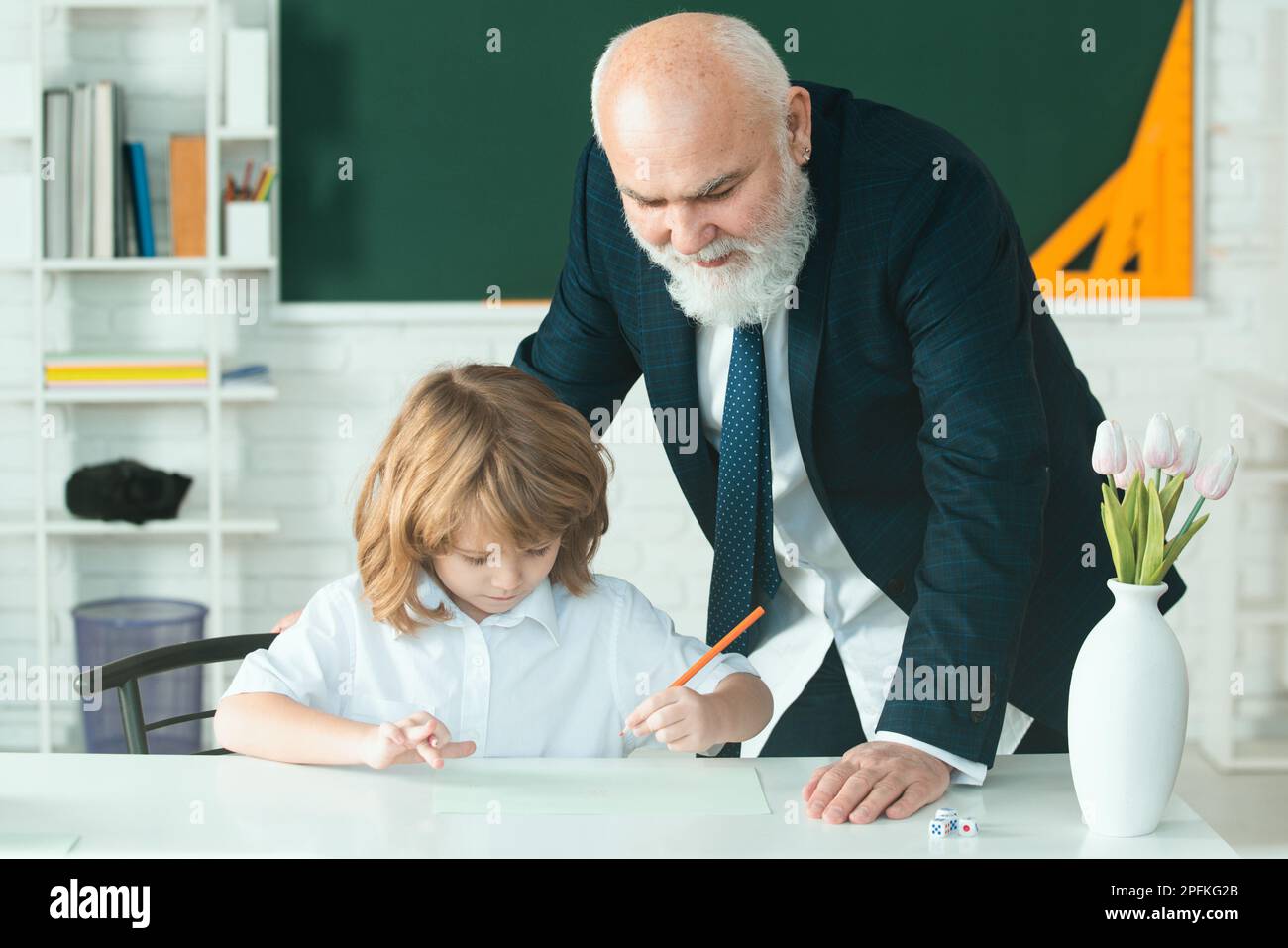 School teacher help to learn. Schoolboy learning in classroom ...