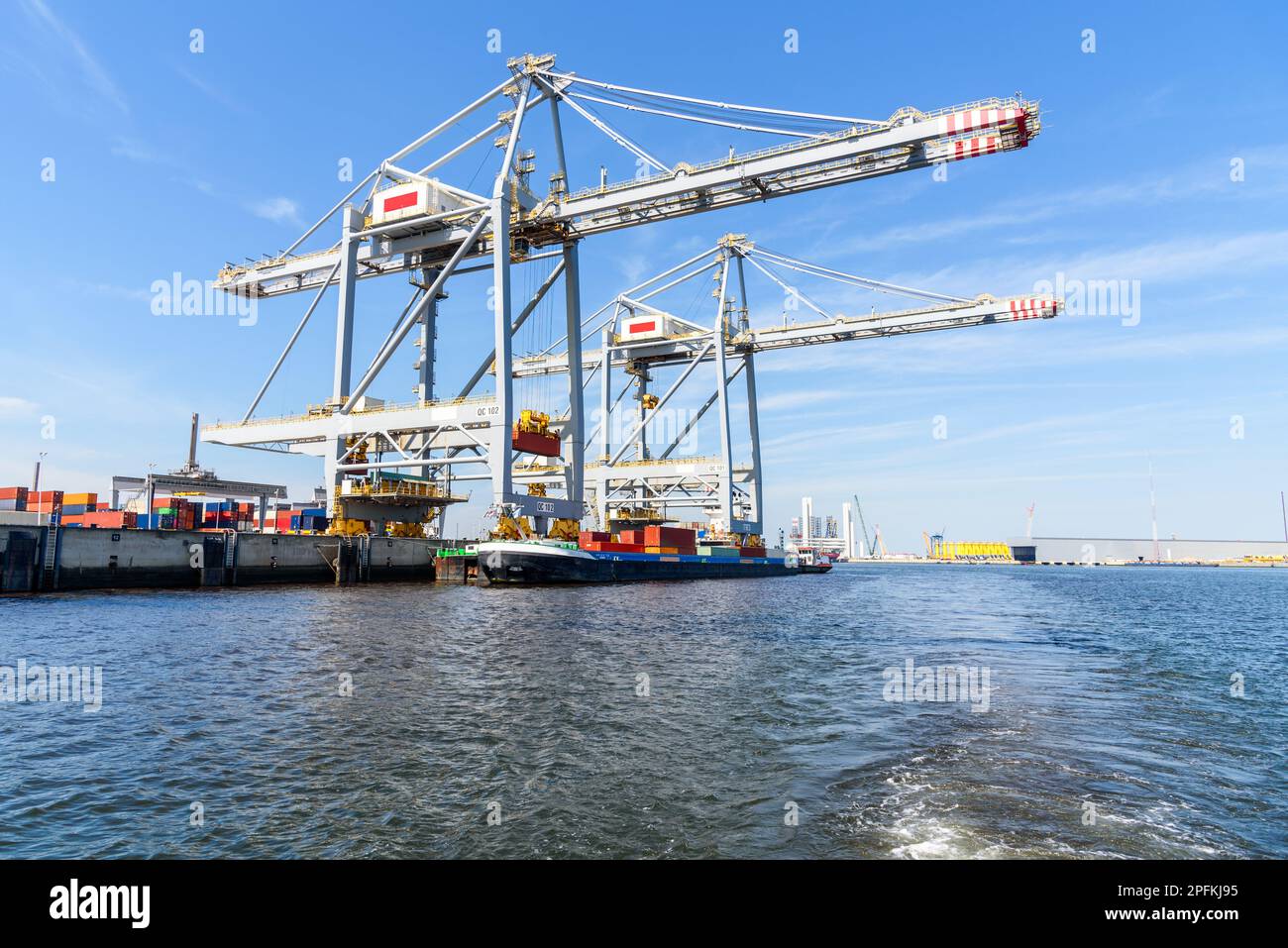 Cargo barge being loaded with containers in a port on a sunny summer ...