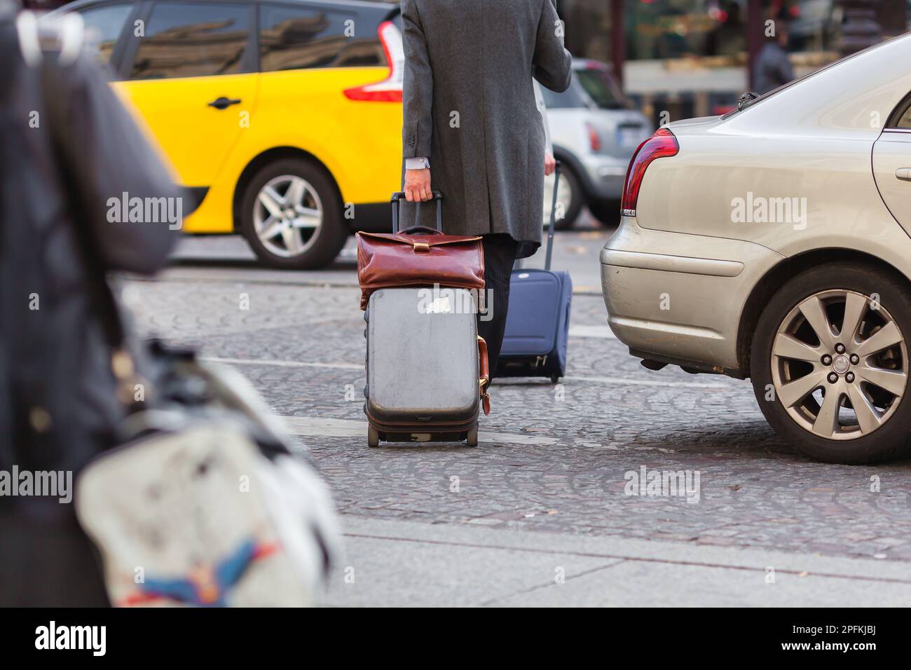 Image of a street scene of an unknown man pulling a wheeled suitcase ...