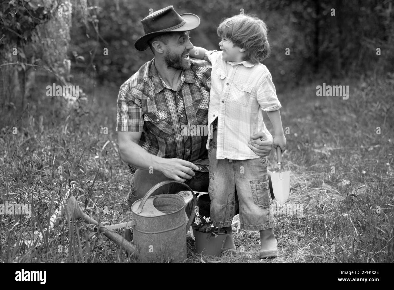 Father and son in nature with watering can. Gardening tools. Planting ...