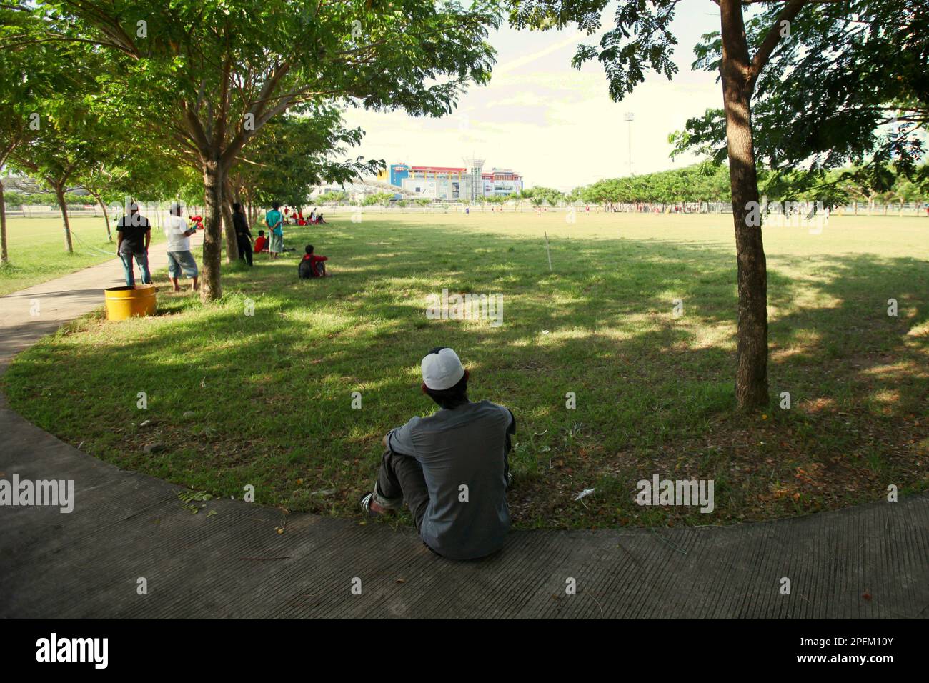A man is sitting on concrete jogging track, overlooking one of the ...