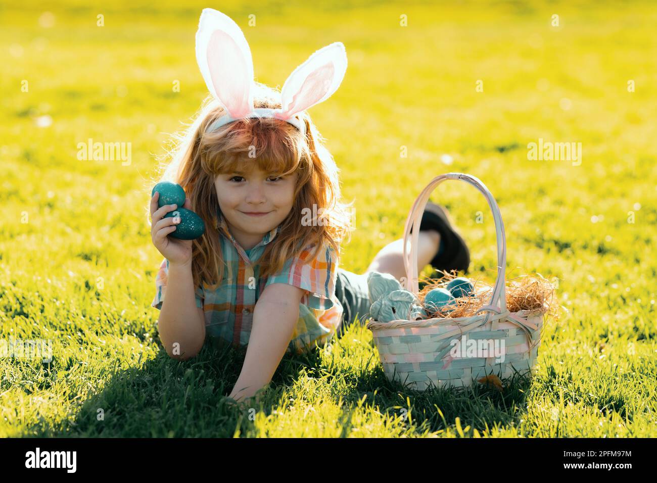 Kids boy in bunny ears hunting easter eggs outdoor. Child having easter ...