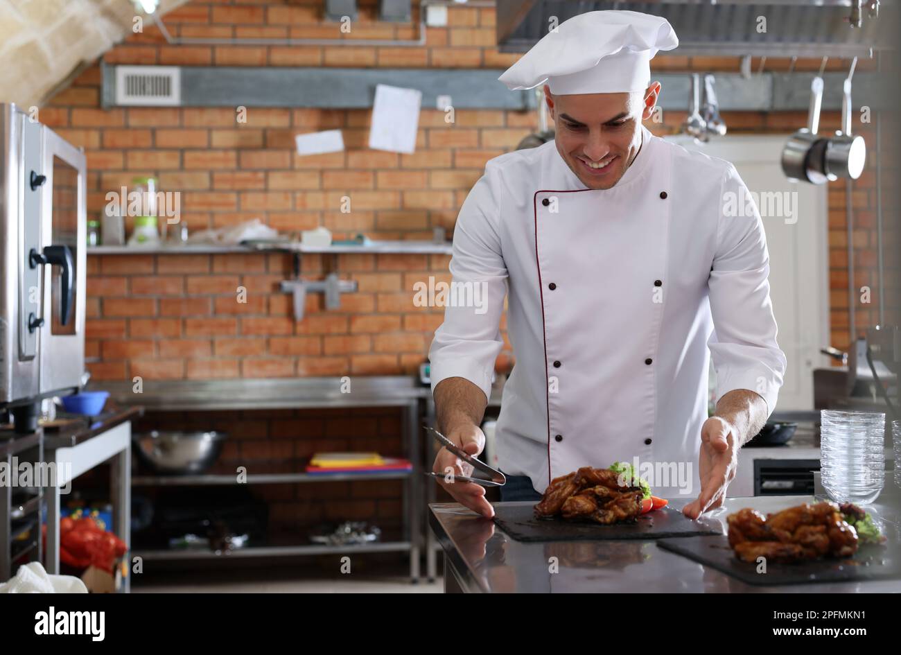 Professional chef with delicious fried chicken wings in restaurant ...