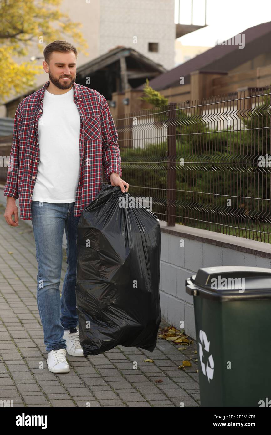Man carrying garbage bag to recycling bin outdoors Stock Photo - Alamy