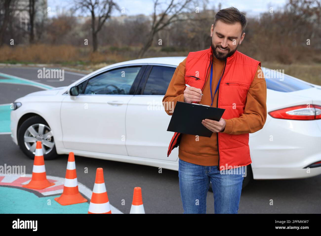 Instructor with clipboard near car on test track. Driving school Stock ...