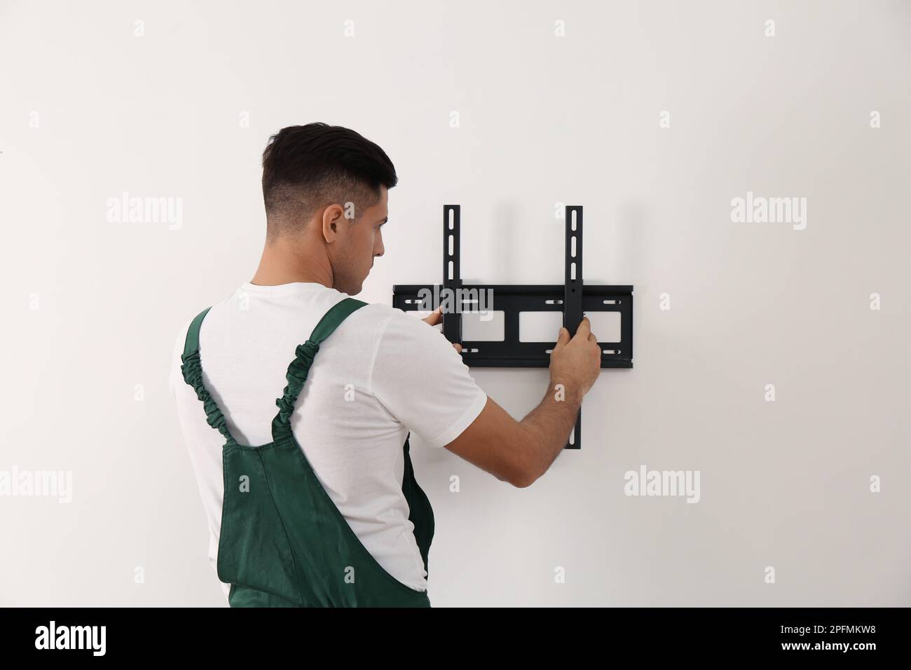 Professional technician installing TV bracket on wall indoors Stock ...