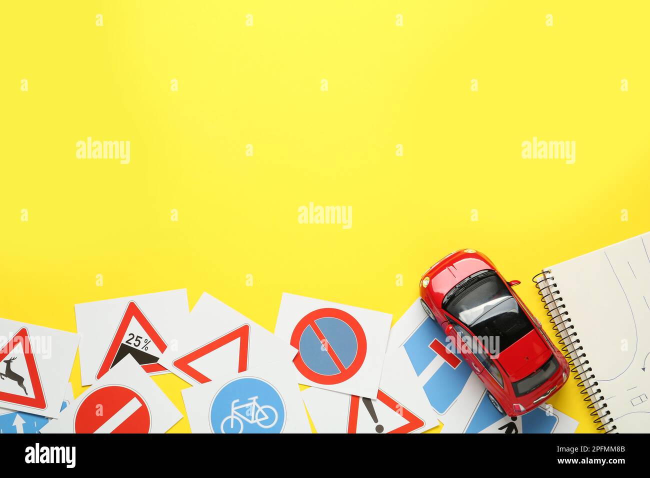 Many different road sign cards, notebook and toy car on yellow ...