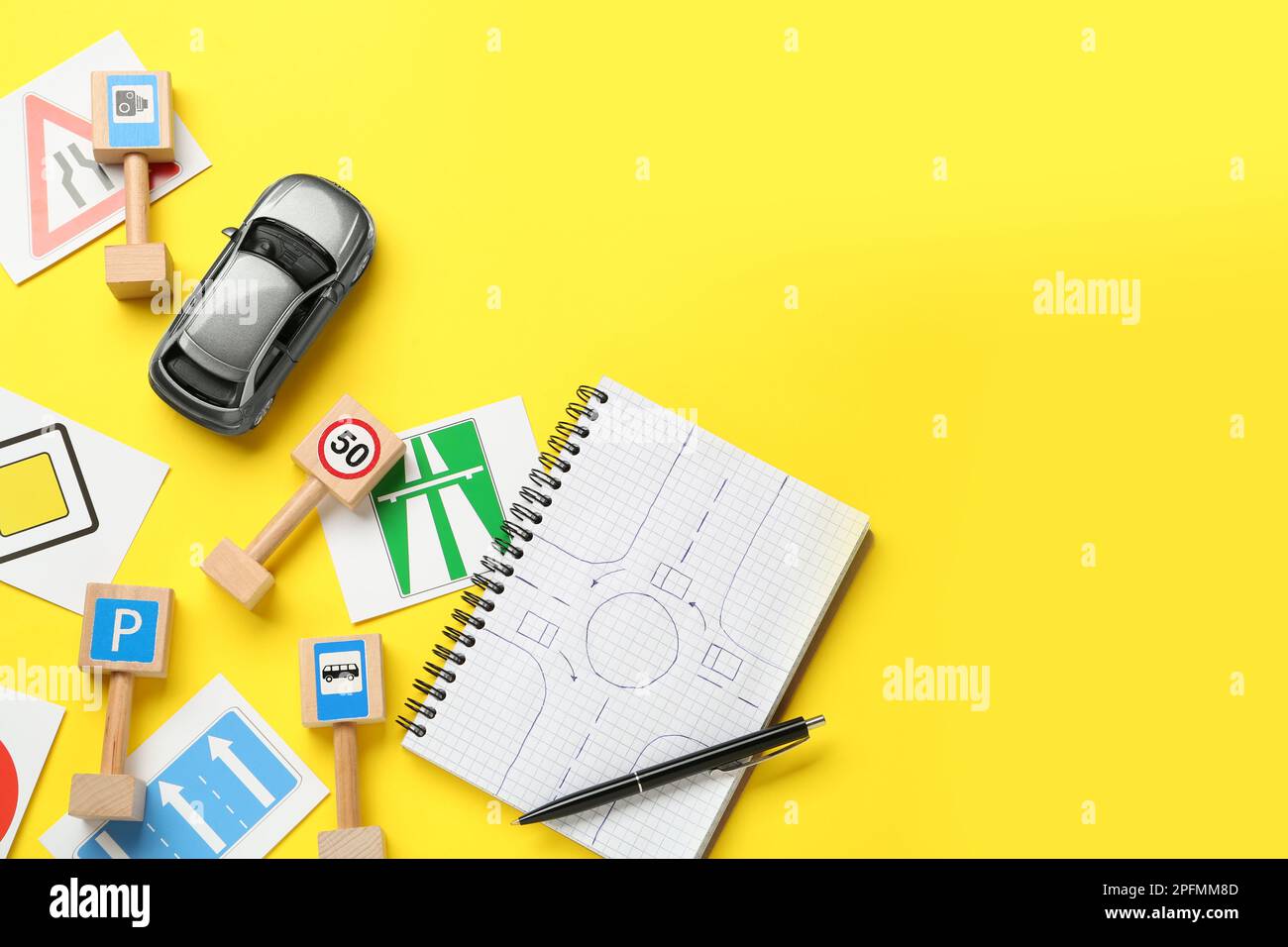 Many different road signs, notebook and toy car on yellow background ...
