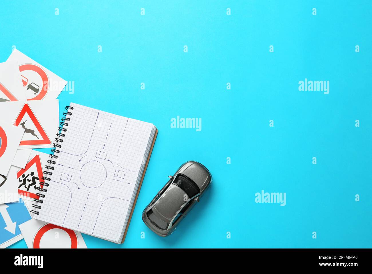 Many different road sign cards, notebook and toy car on light blue ...