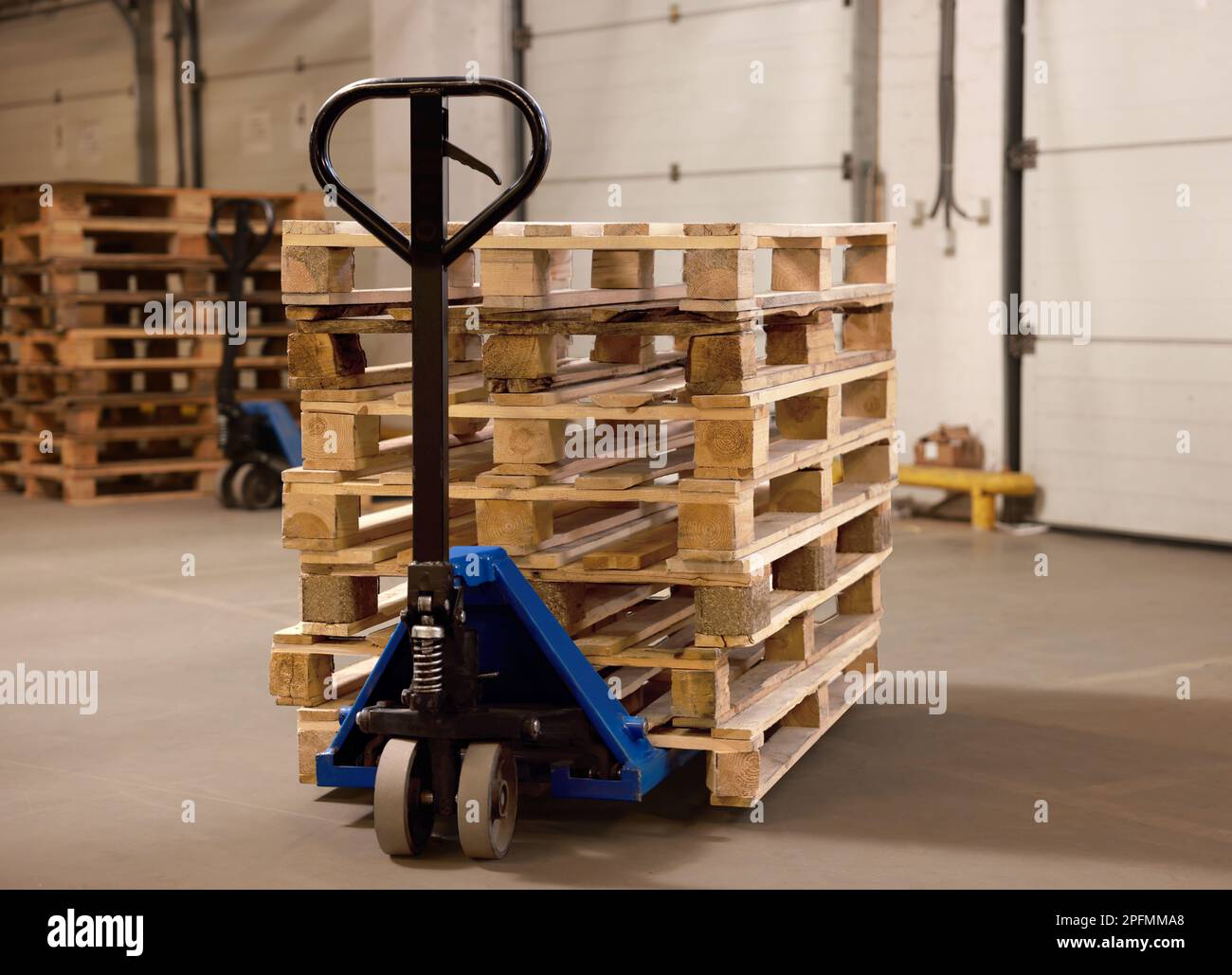 Modern manual forklift with wooden pallets in warehouse Stock Photo - Alamy