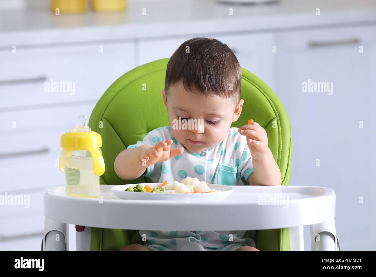 Cute little baby eating healthy food in high chair at home Stock Photo ...