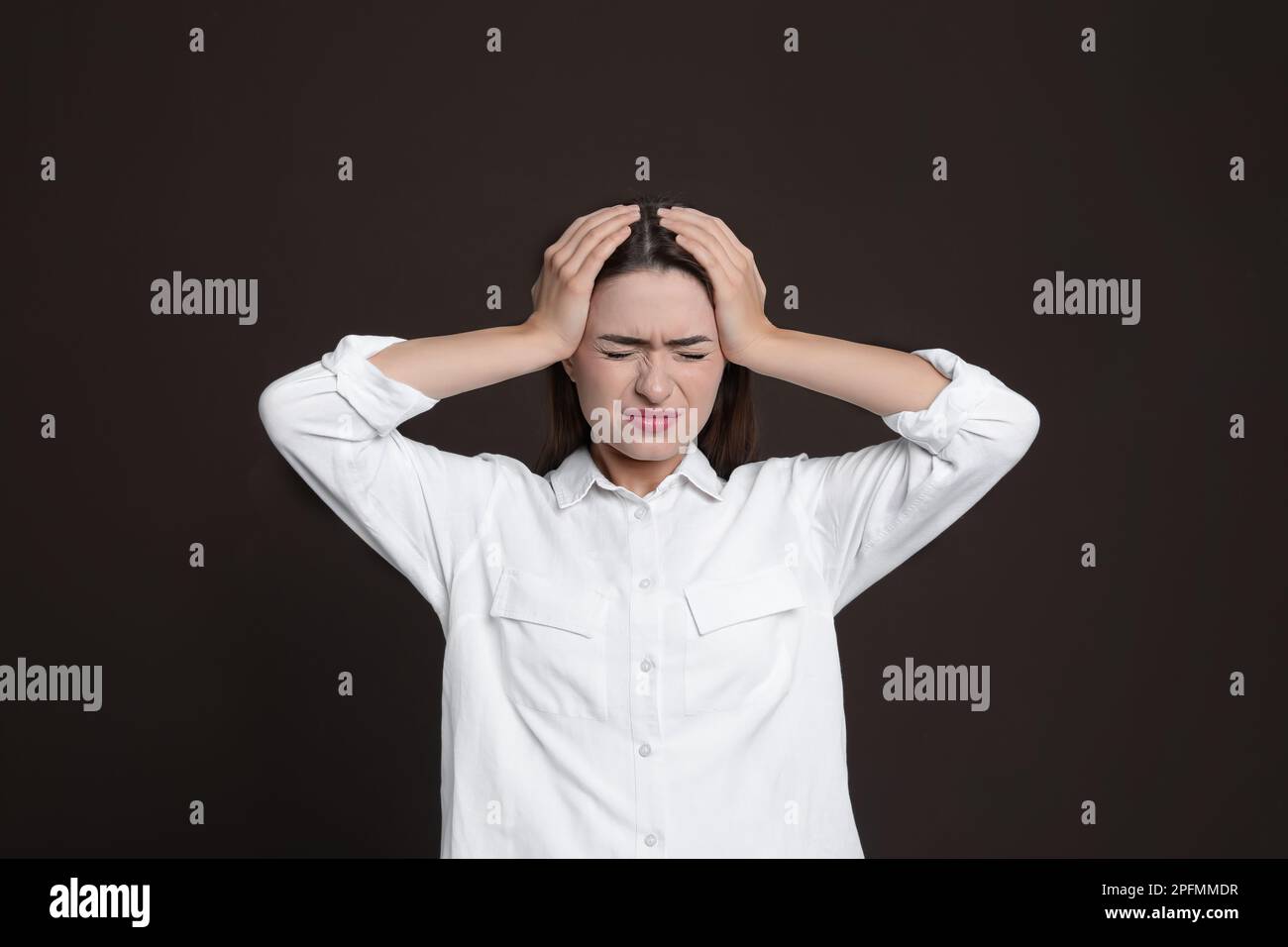 Young woman suffering from headache on brown background Stock Photo - Alamy