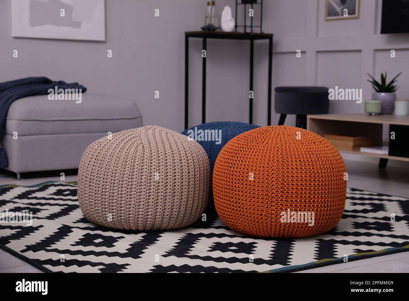Different stylish poufs on floor in living room Stock Photo - Alamy