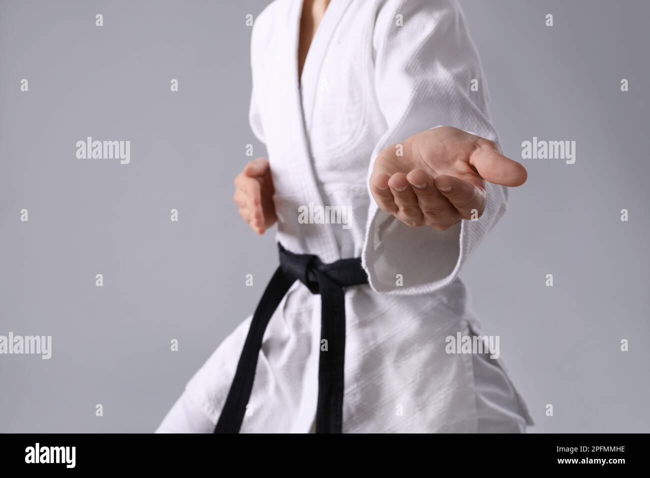 Martial arts master in keikogi with black belt against grey background ...