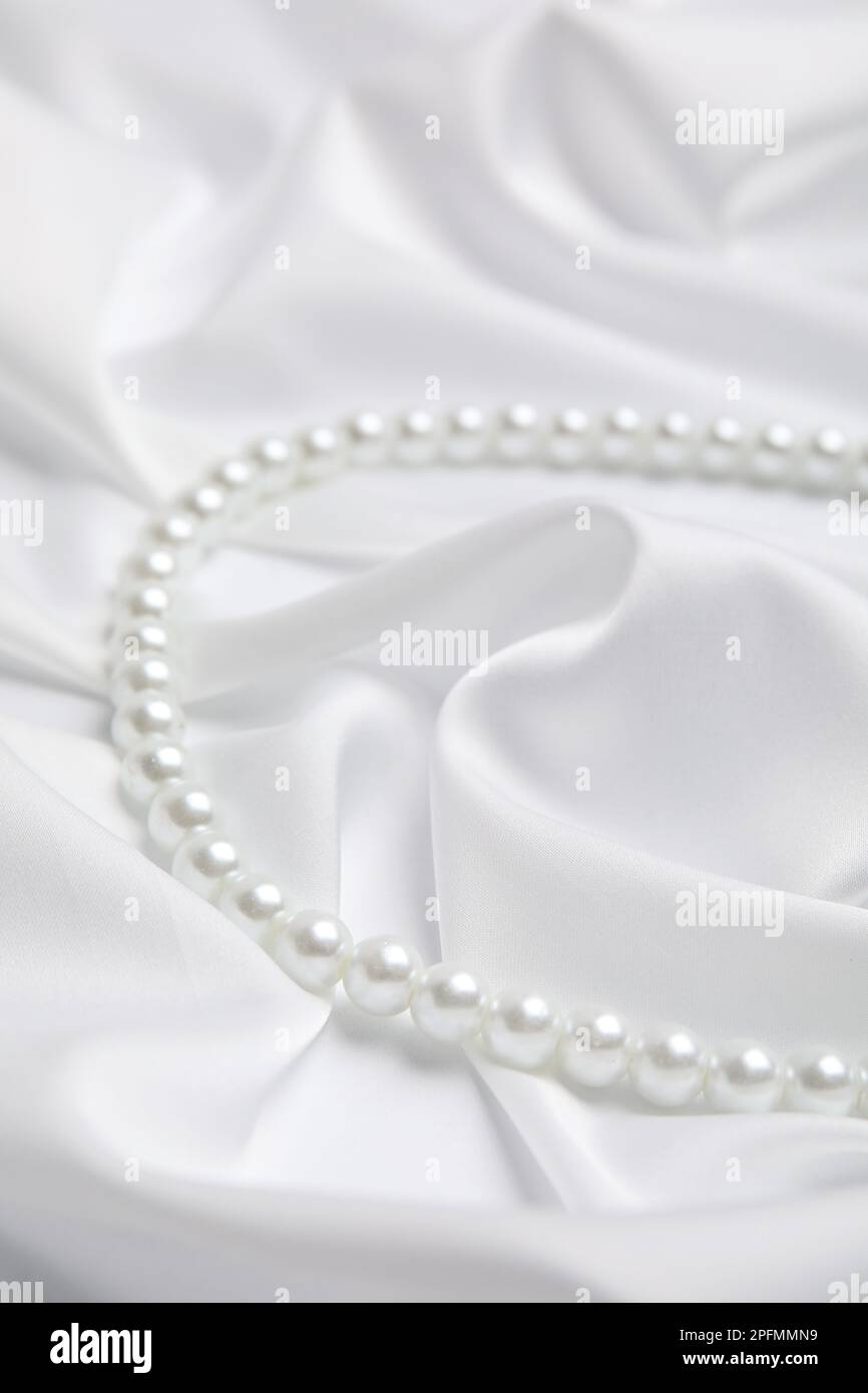 Beautiful pearls on white silk, closeup view Stock Photo - Alamy
